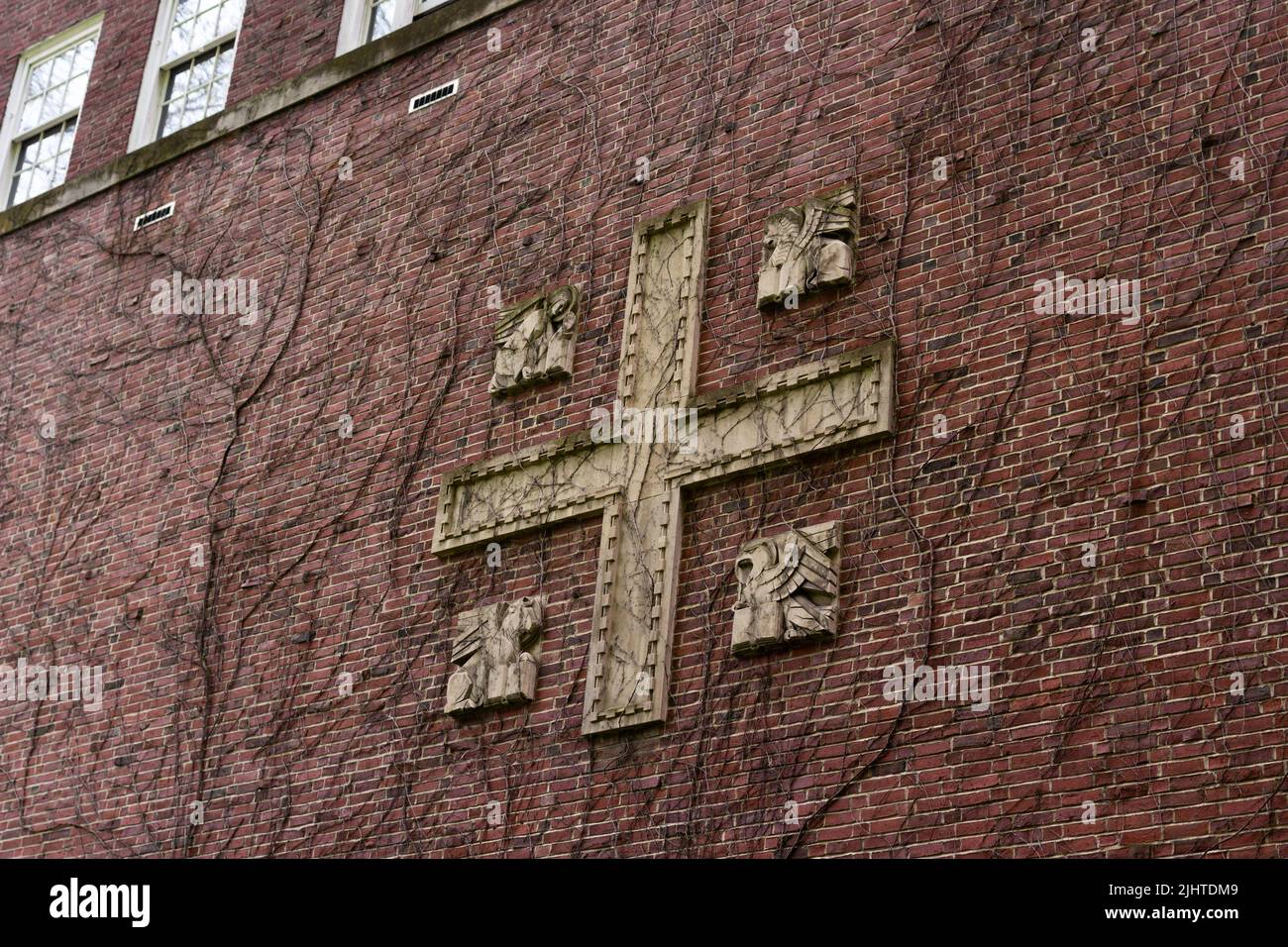 Medieval red brick wall with cement cross. Branches branch over the ...