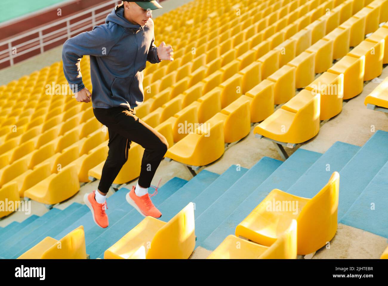 Young sportsman running up the stairs while working out at stadium ...