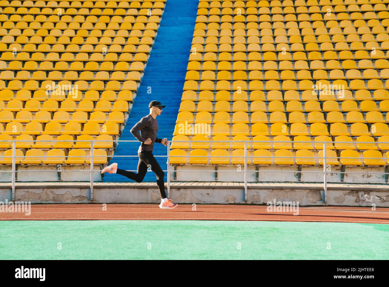 Young white sportsman running while working out on stadium outdoors ...
