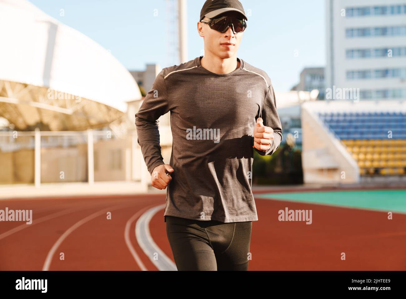 Young white sportsman running while working out on stadium outdoors ...