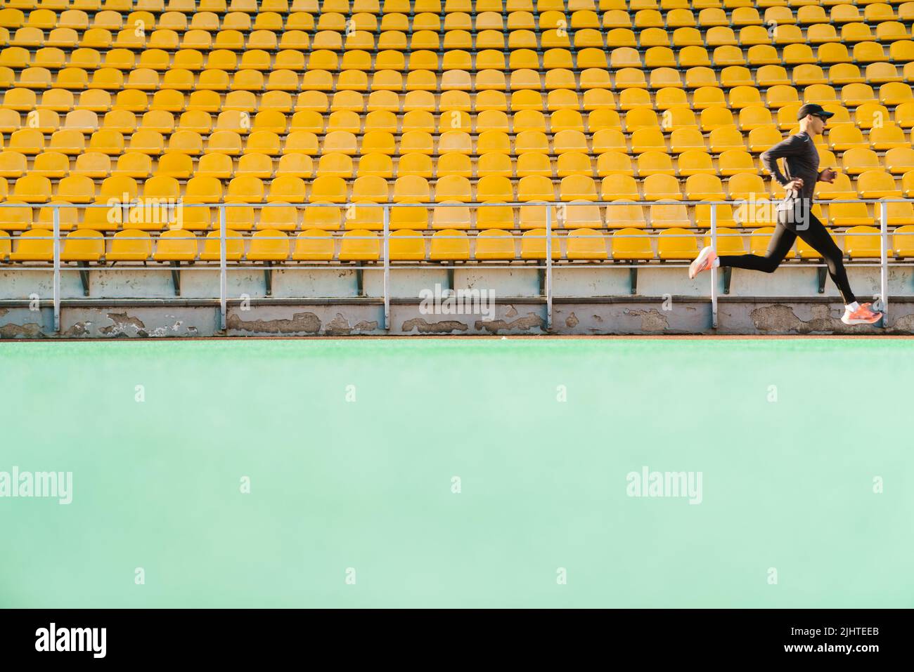 Young white sportsman running while working out on stadium outdoors ...