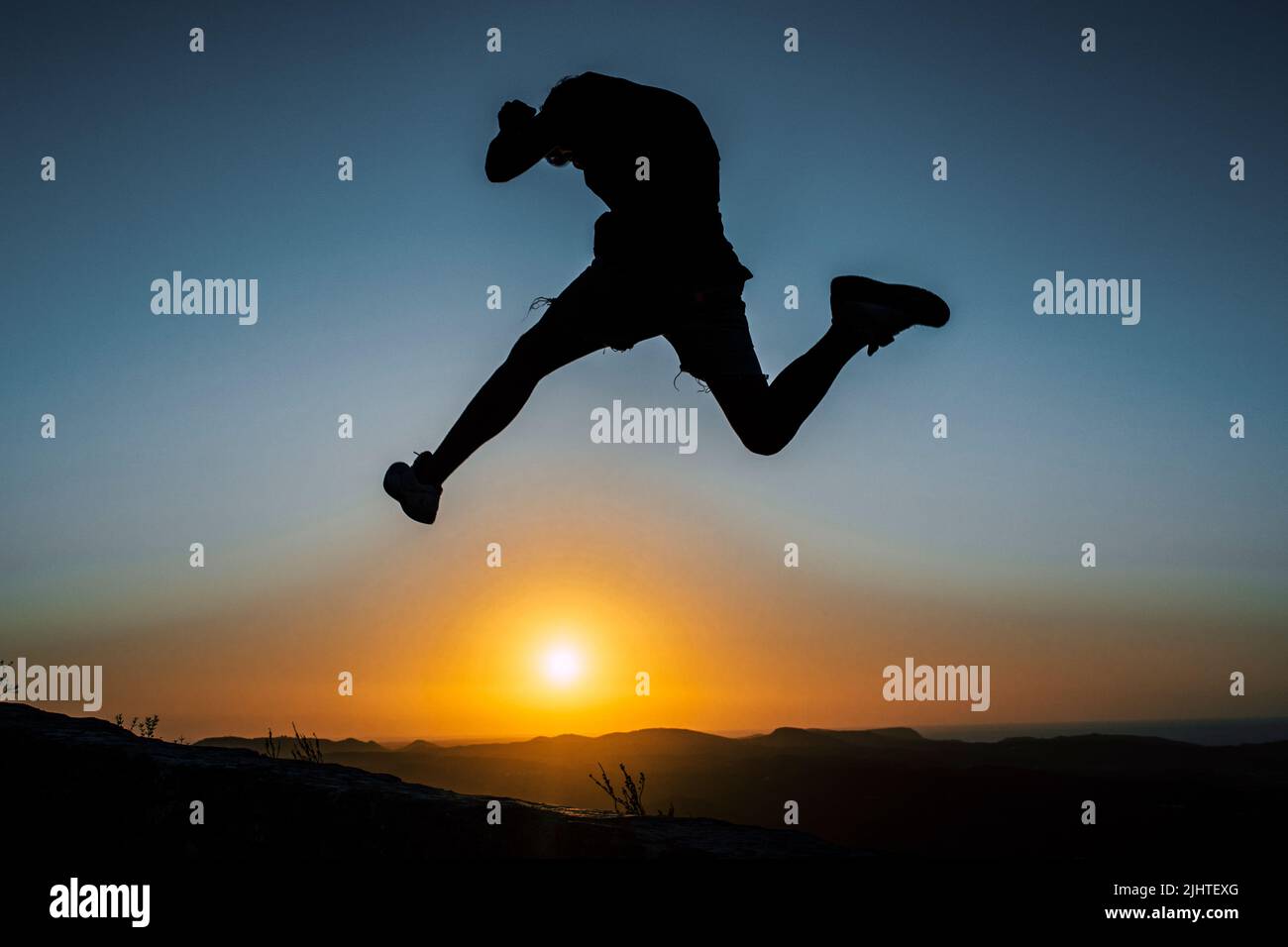 Silhouette of a boy jumping with the sunset behind him. Summer feelings ...