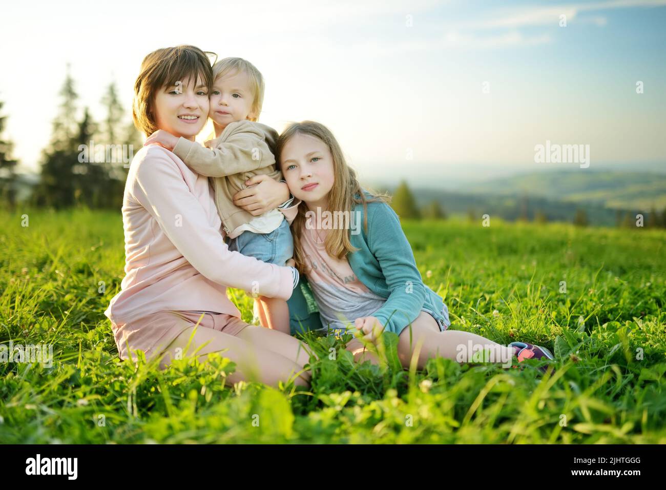 Two sisters and their toddler brother having fun outdoors on sunny ...
