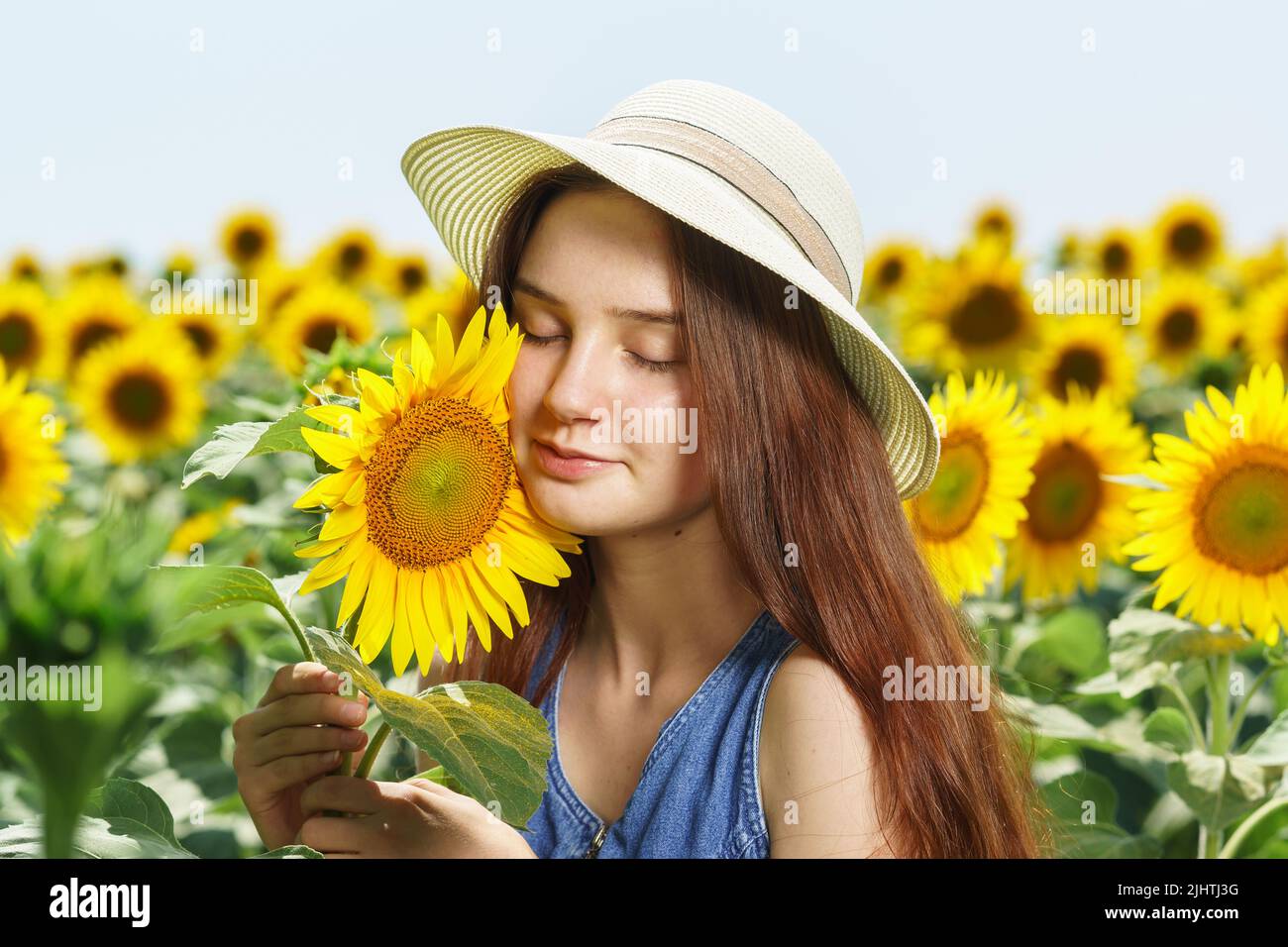 Portrait of a beautiful happy girl with long hair in a blue sundress ...