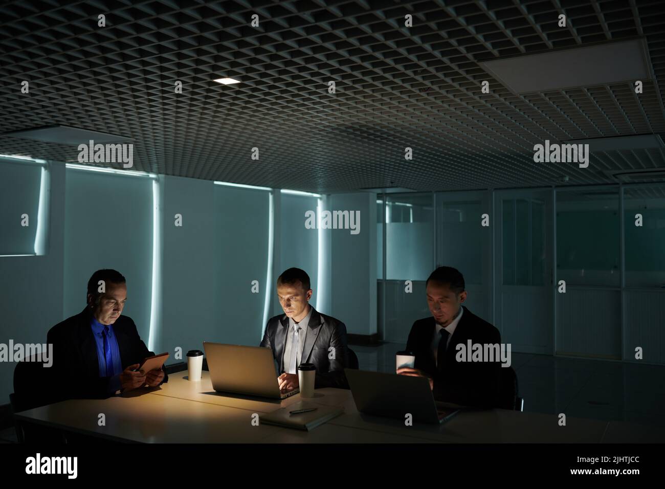 Group of serious business people working on secret project in dark ...