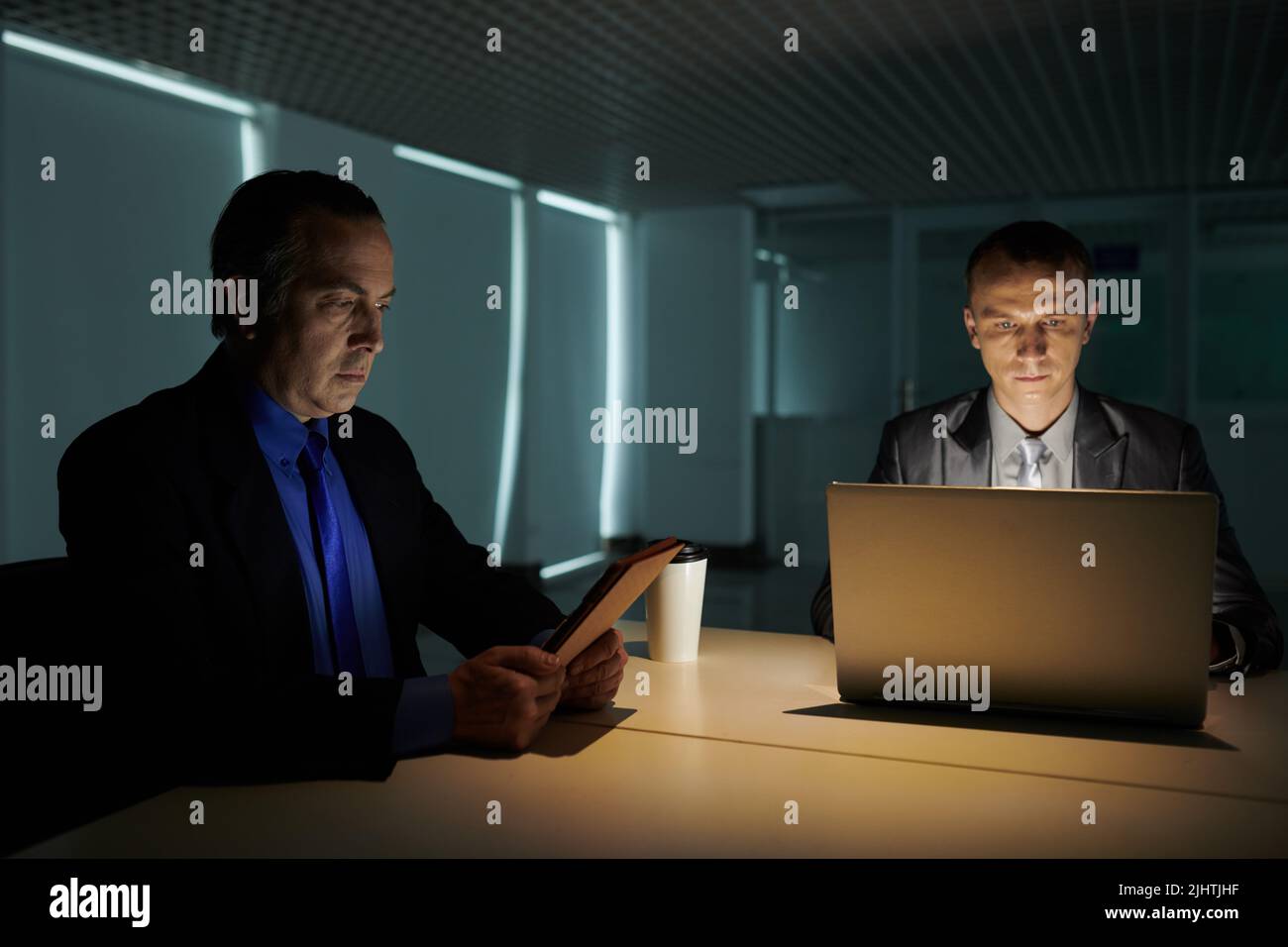 Business team working in dark office late at night and reading ...