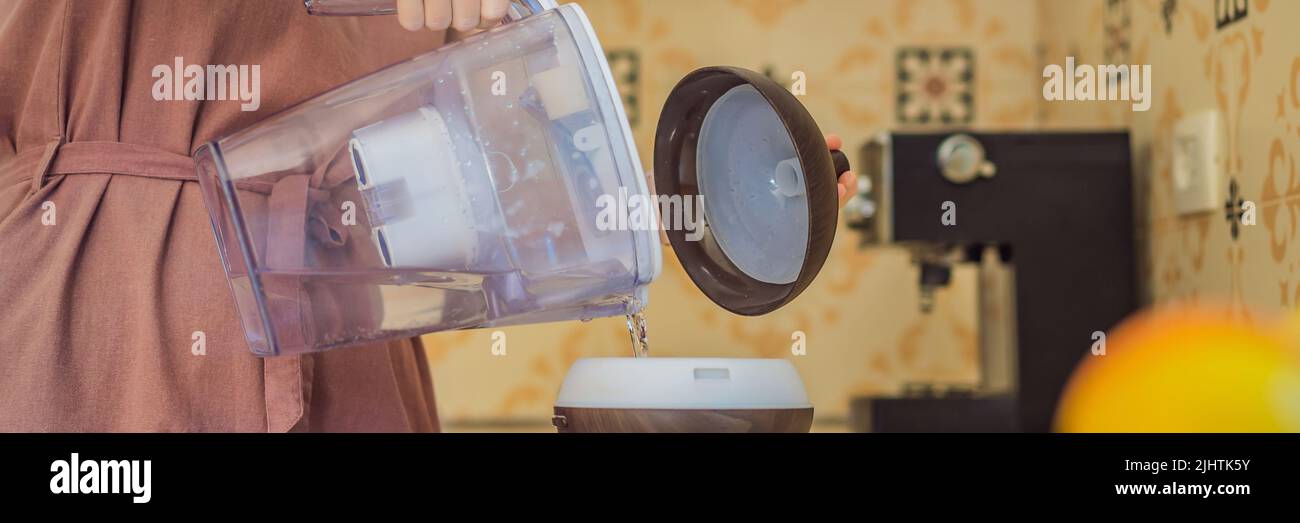 BANNER, LONG FORMAT Woman pouring water into an aroma diffuser ...