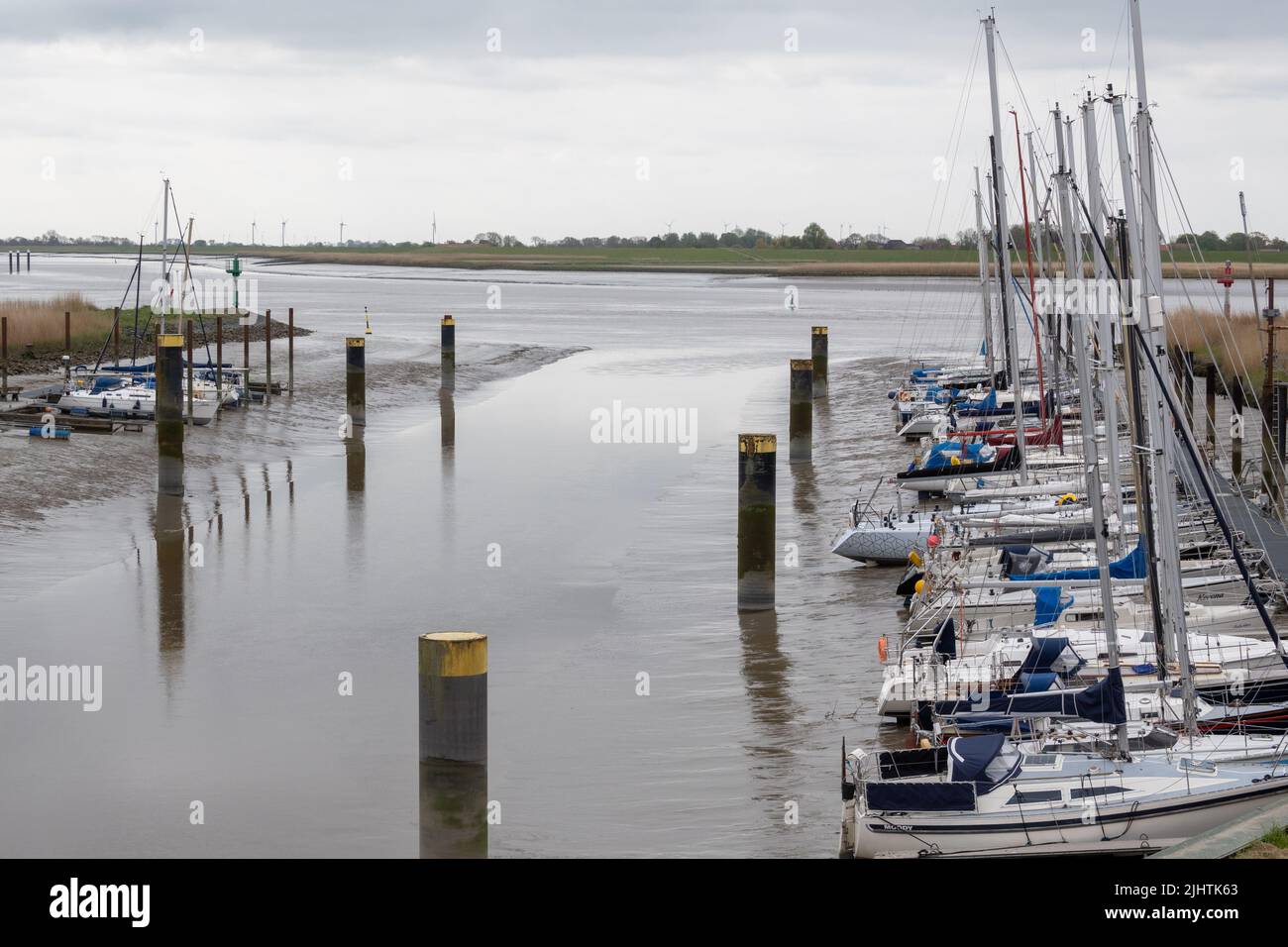 A low tide in a harbor with row of boats tied to a float Stock Photo ...
