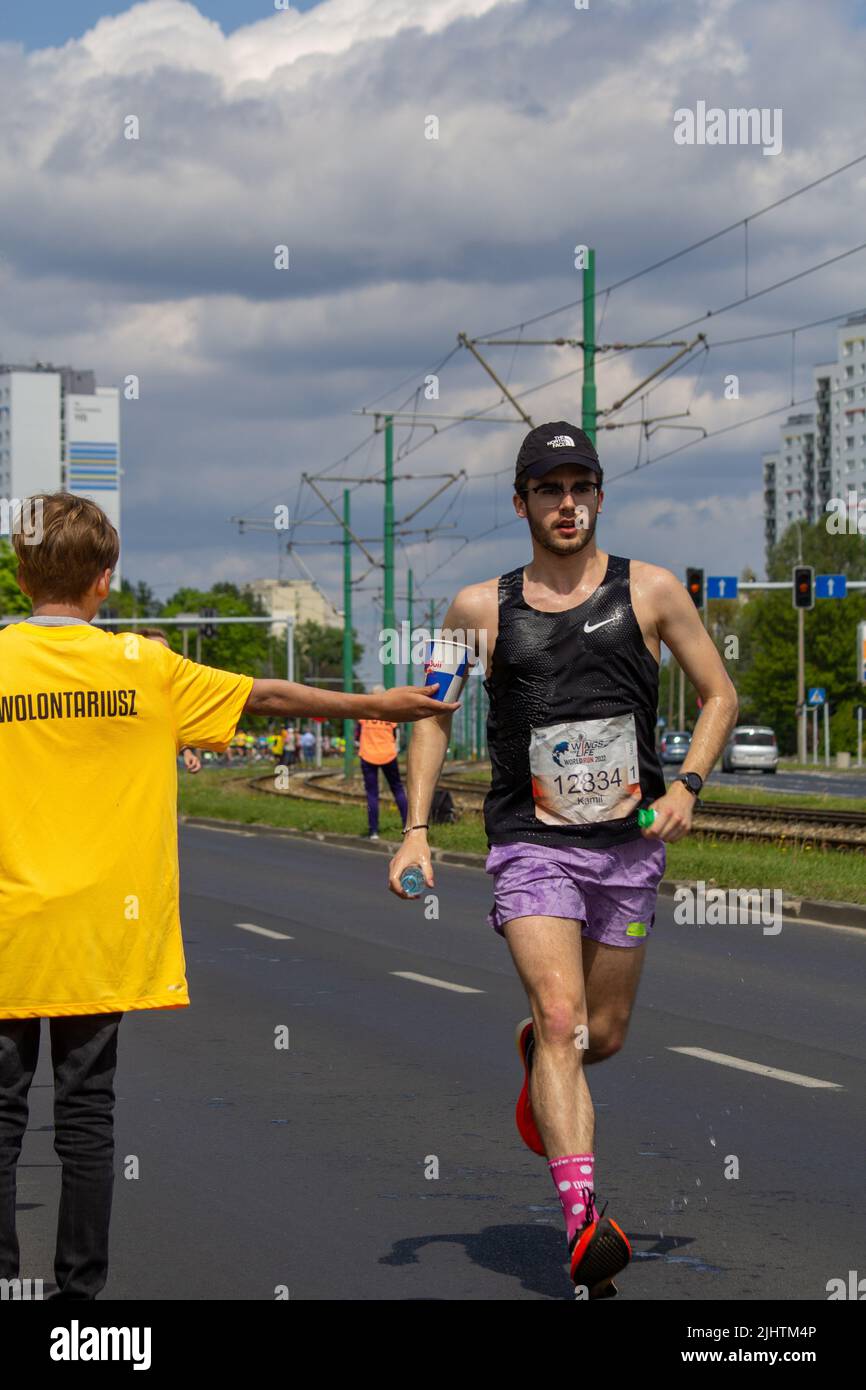 The volunteer offering water to the runner at Wings for Life World Run ...