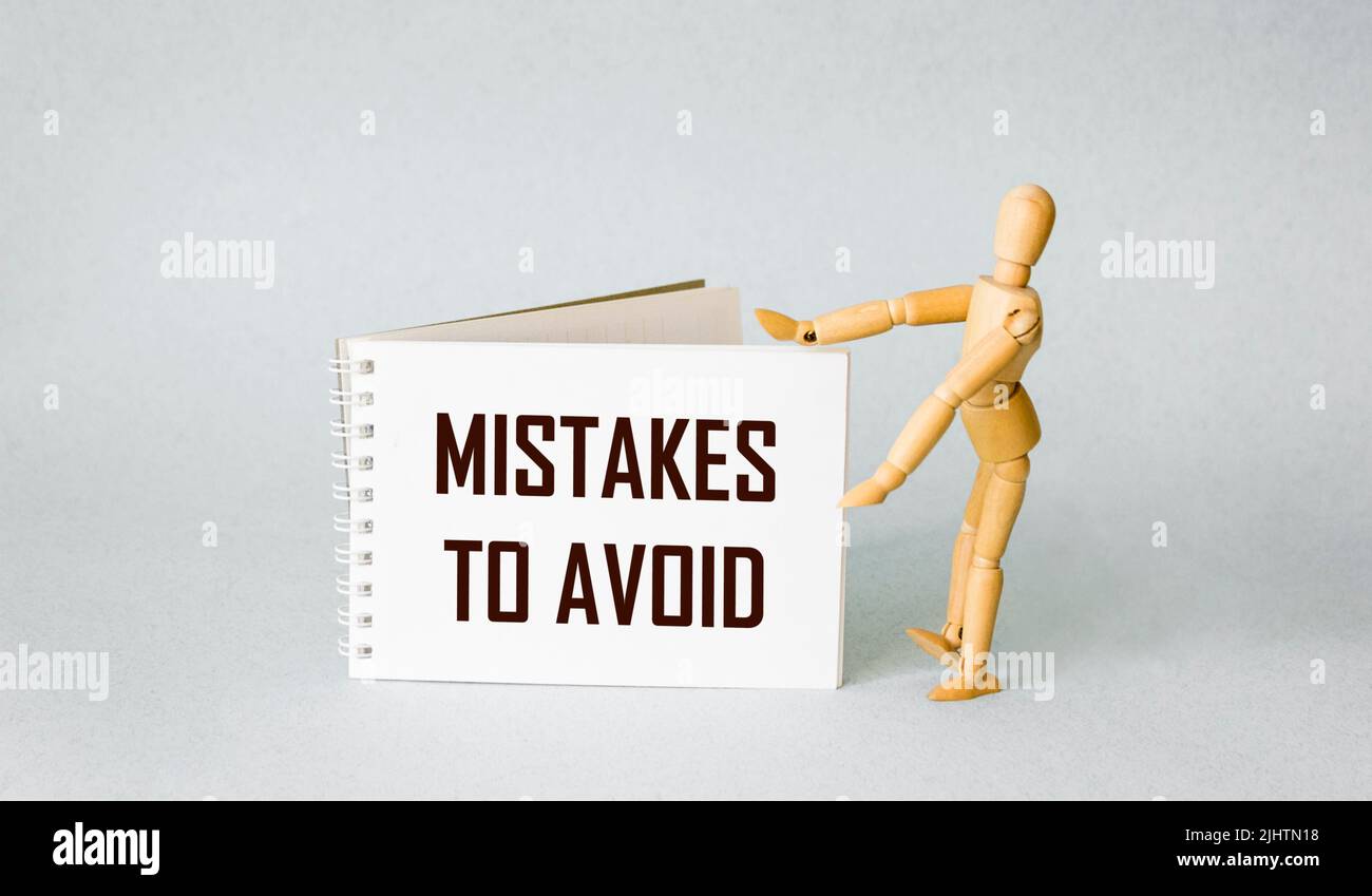 Notepad with text errors to avoid with a wooden doll on a light ...