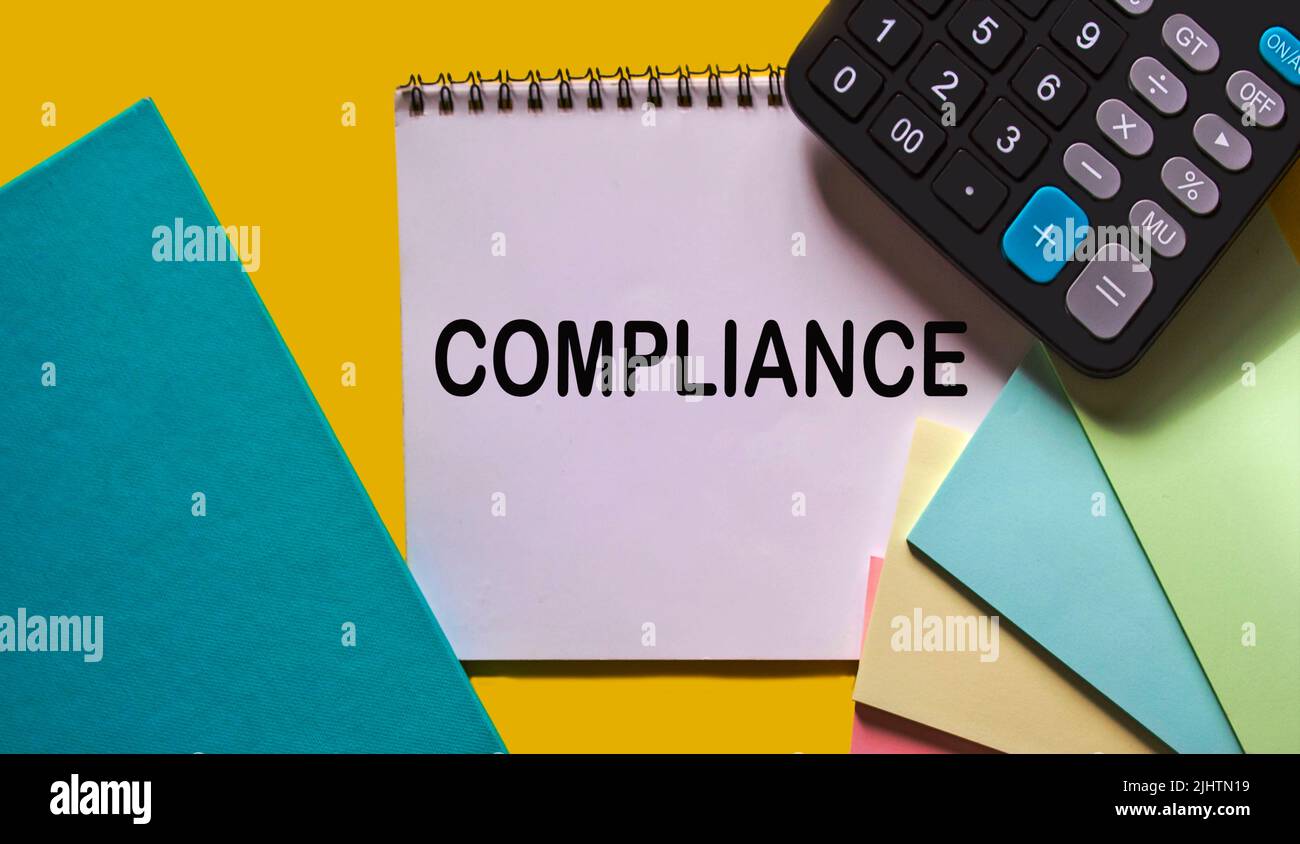 Word COMPLIANCE on notepad with calculator, notepad and stickers on ...