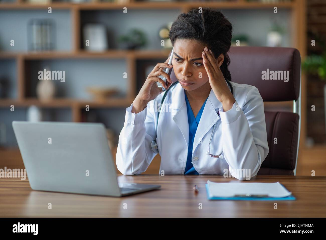 Overworked black woman doctor having phone conversation Stock Photo - Alamy