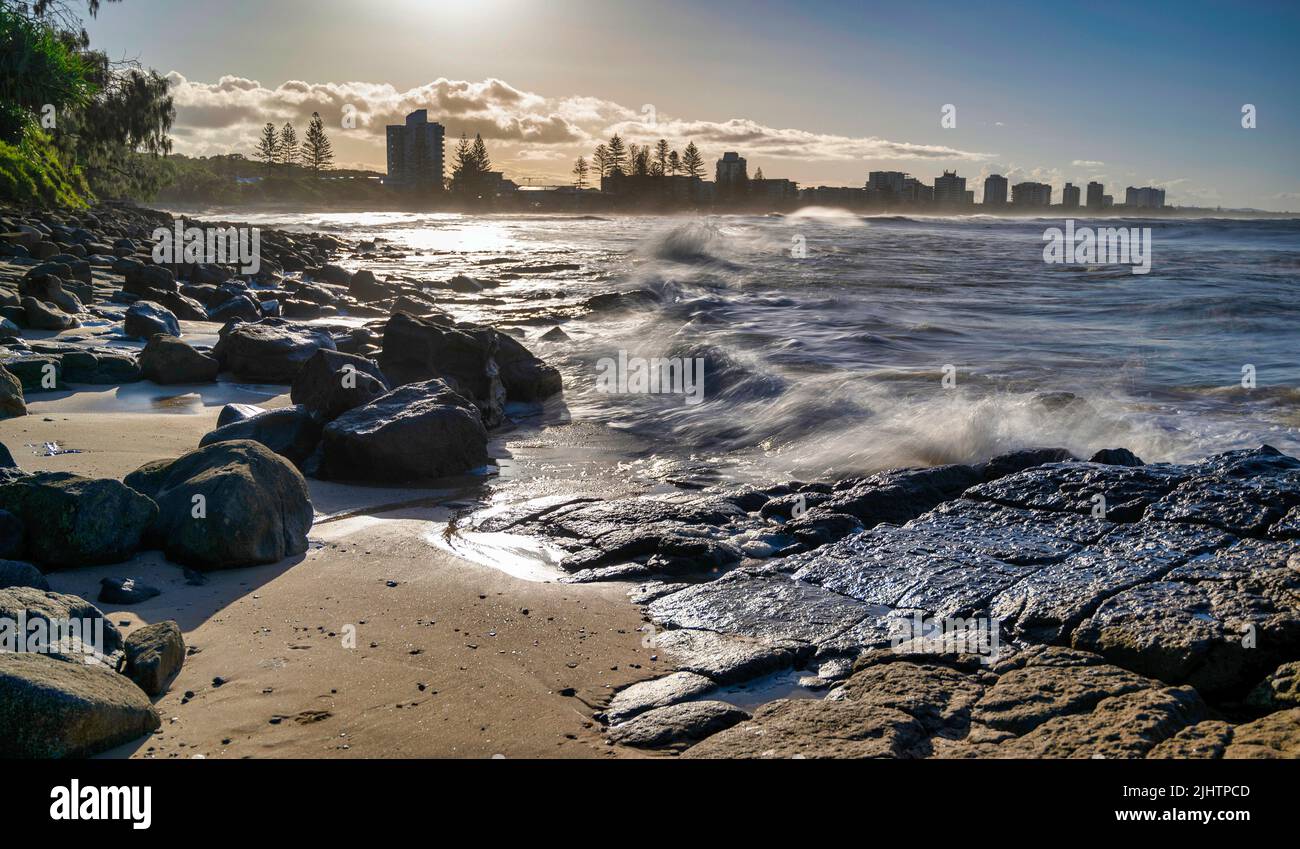 A rocky sun-drenched beach lapped by soft sea waves against the ...