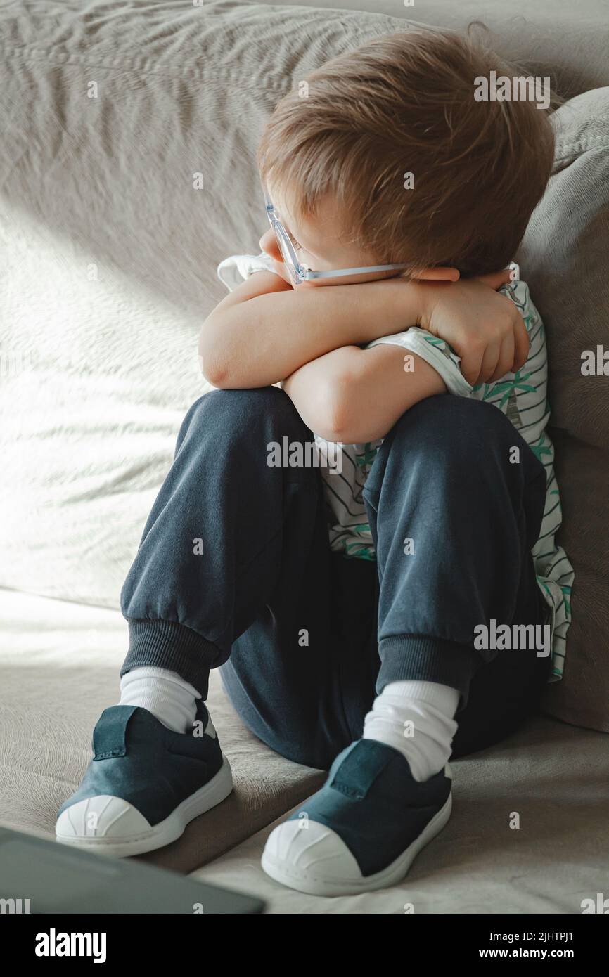 Child with autism in glasses sits on the sofa and sad Stock Photo - Alamy