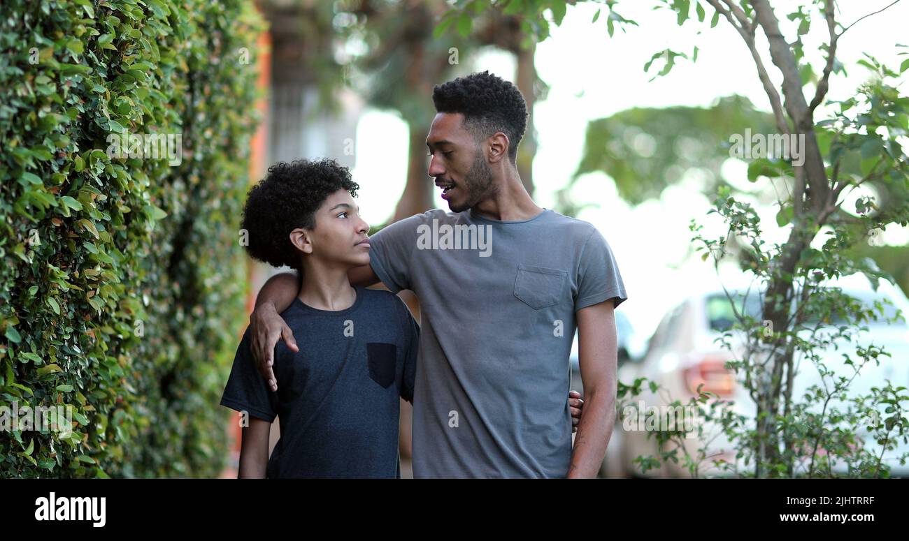 Two brothers walking together in sidewalk. Black brother giving advice ...