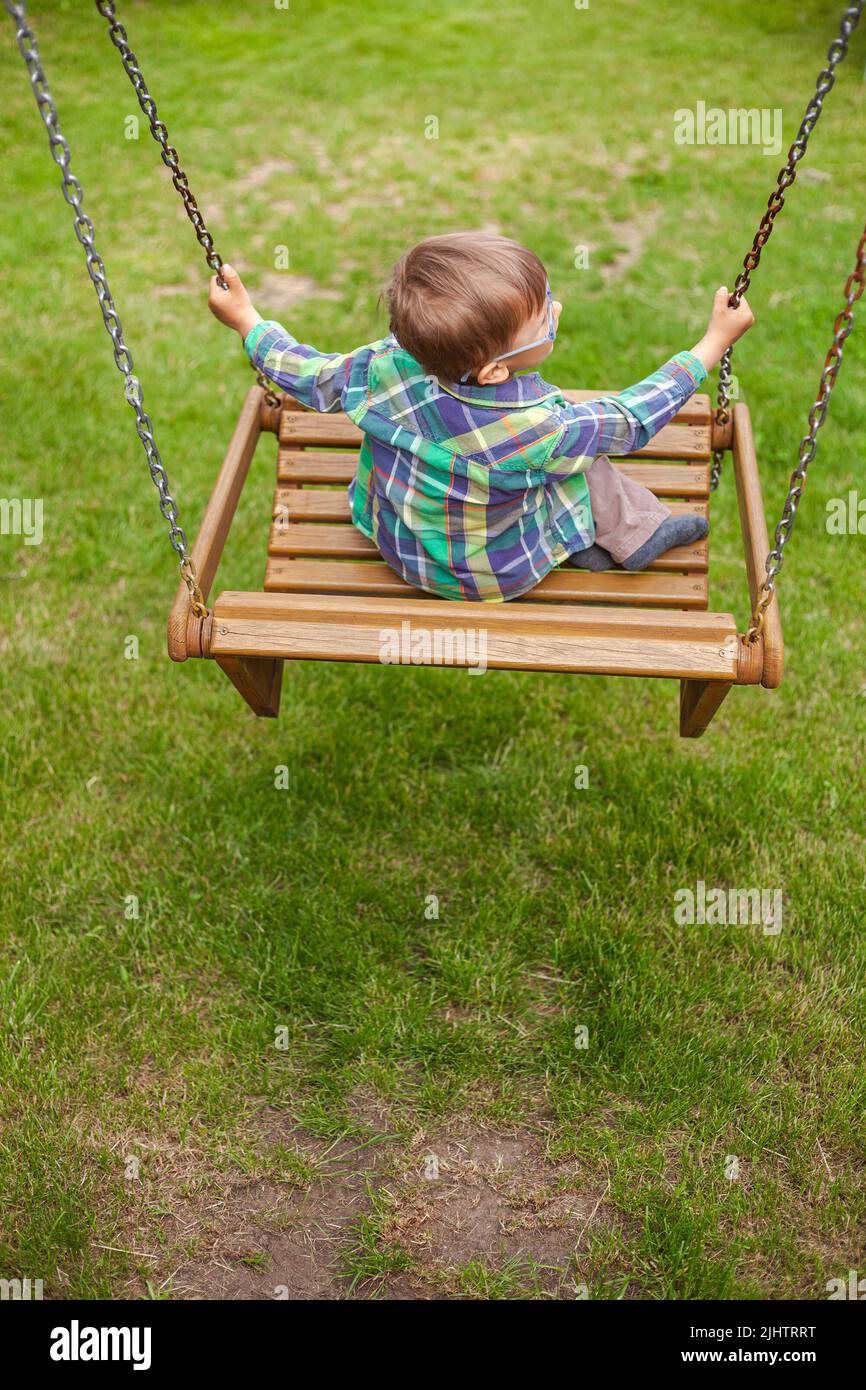 Child swinging on swing in the backyard Stock Photo - Alamy