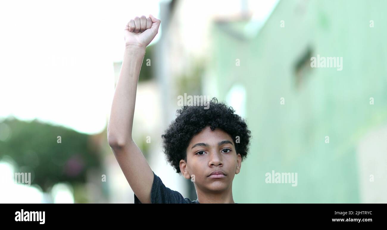 Young black boy raising fist in the air, kid looking at camera in ...