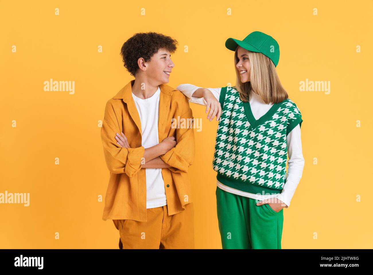 White two teenagers smiling while posing together isolated over yellow ...