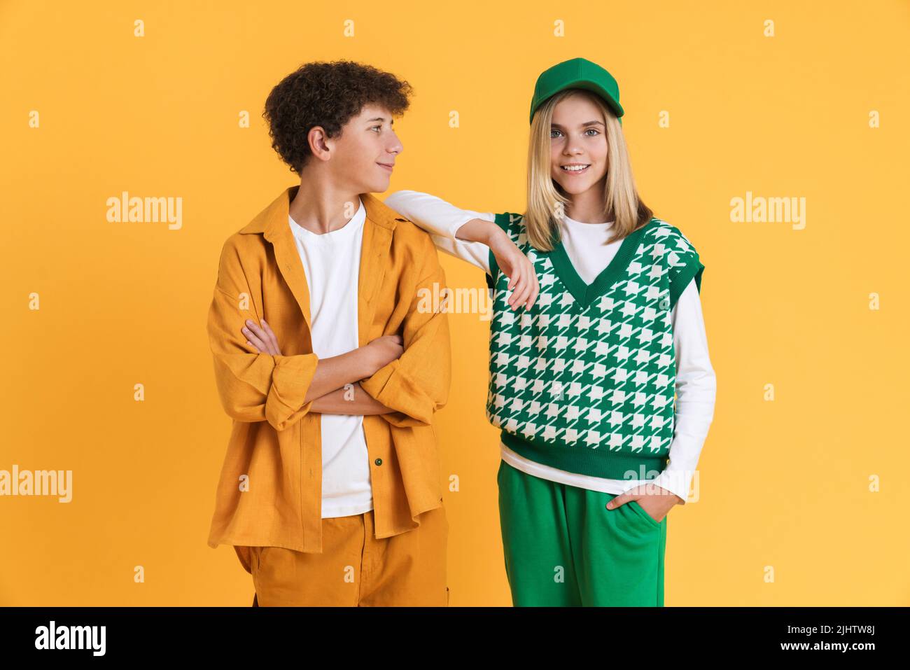 White two teenagers smiling while posing together isolated over yellow ...