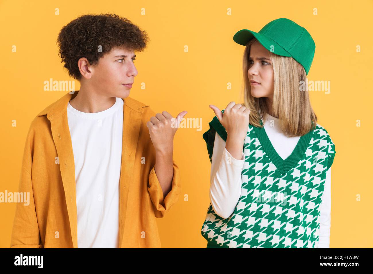 White girl and boy frowning while pointing fingers at each other ...
