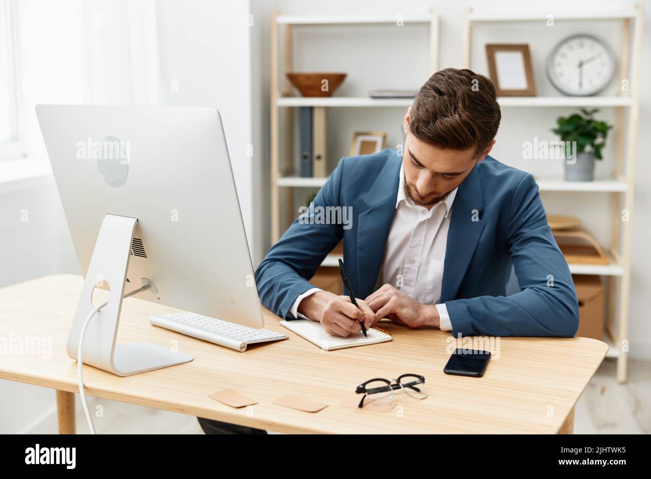 manager writes in documents at the desk in the office Gray background ...