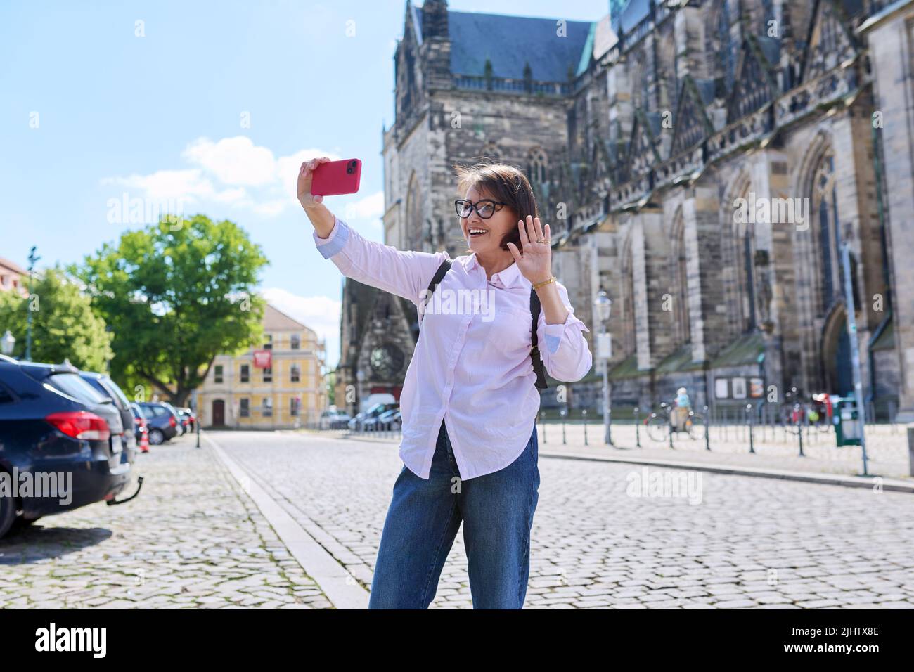 Woman tourist taking a selfie in front of an ancient European cathedral ...