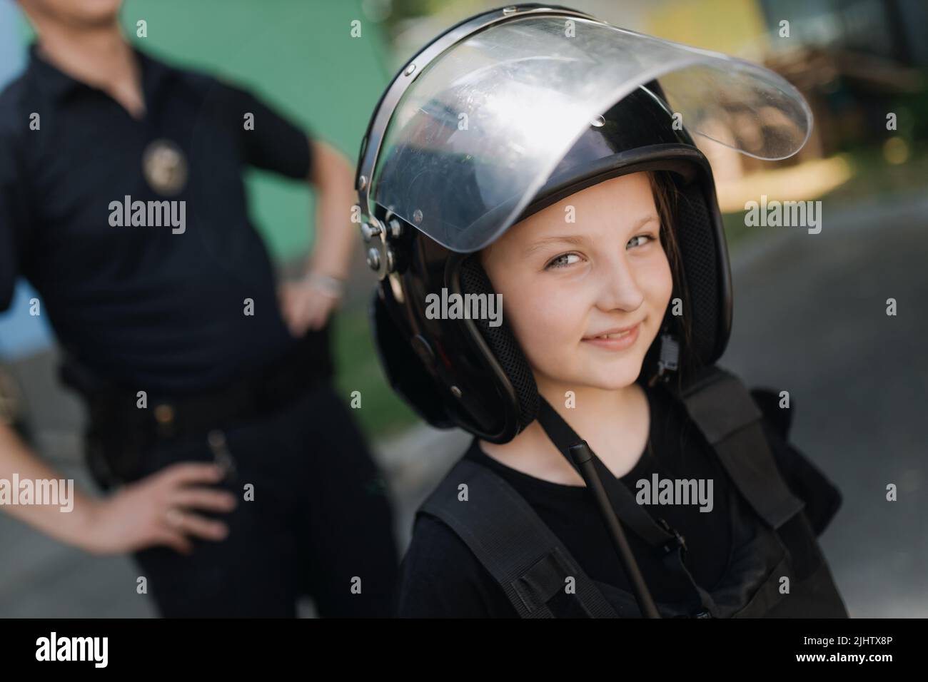 European child girl in a police helmet looks at the camera while ...