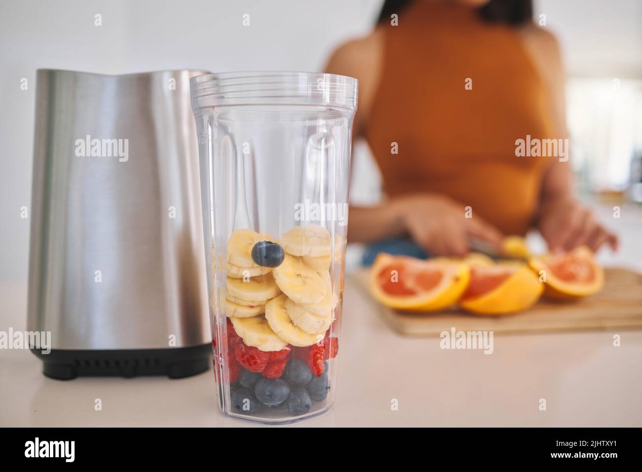 All you need is a smoothie. a woman putting a variety of fruits into a ...