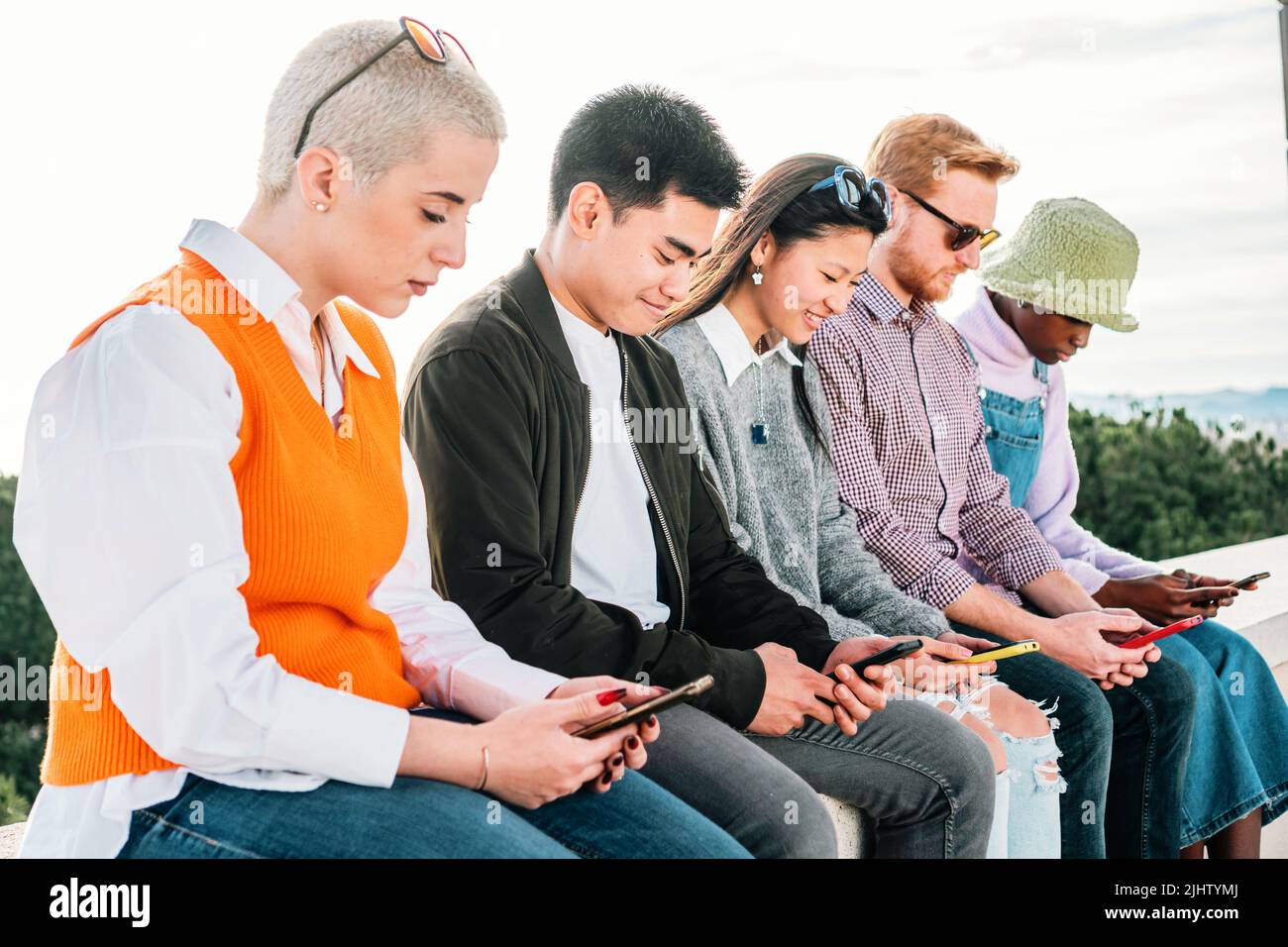 Five friends browsing in internet with their smartphones sitting ...