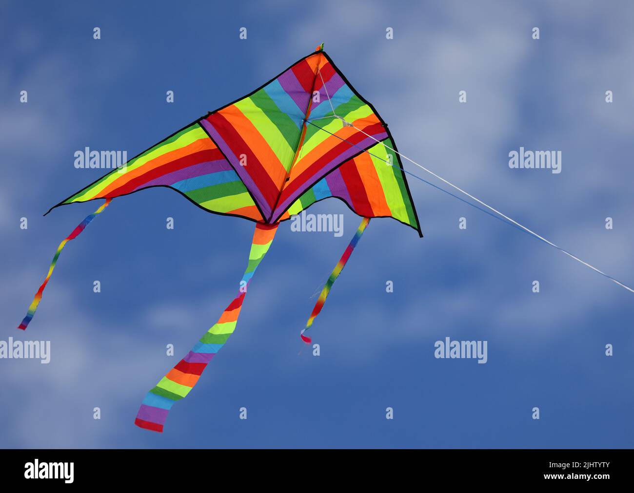 colorful triangular kite flying high in the blue sky with some white ...