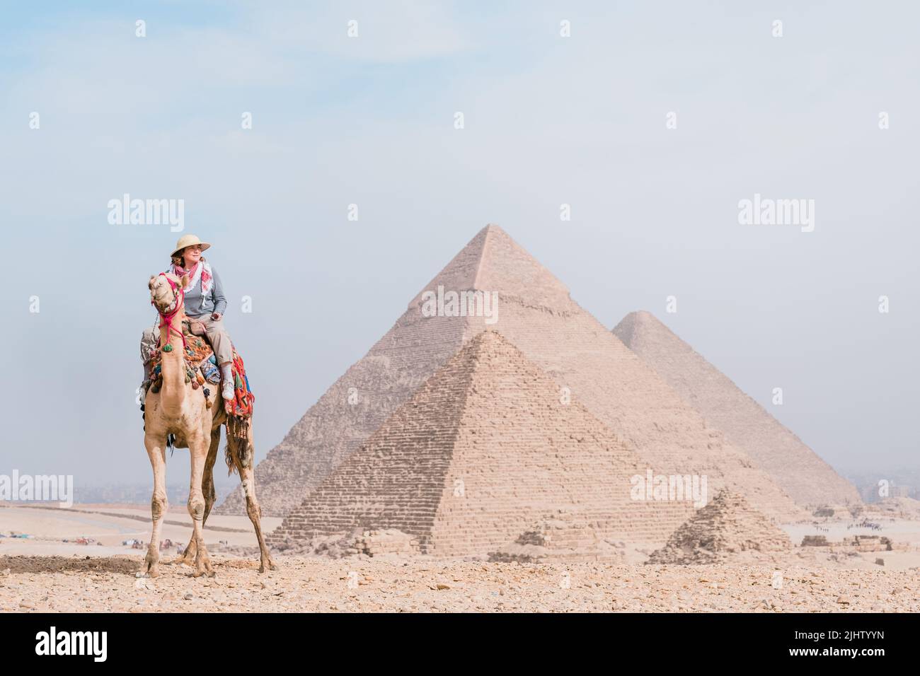 tourist woman riding a dromedary in front of pyramids. Egypt, Cairo ...