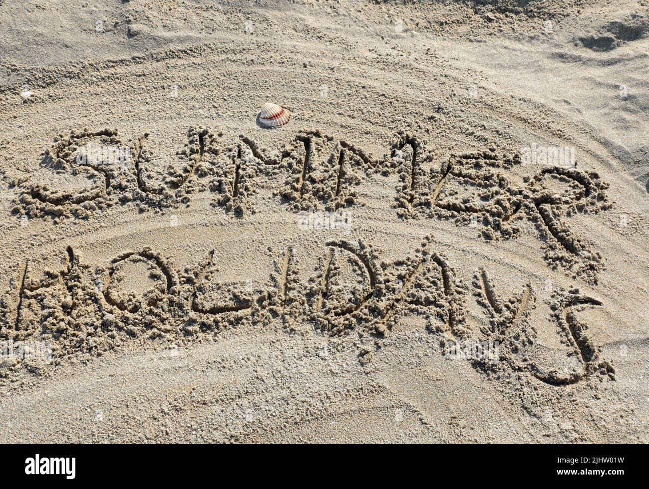 text with the words SUMMER HOLIDAYS in capital letters on the sand of ...