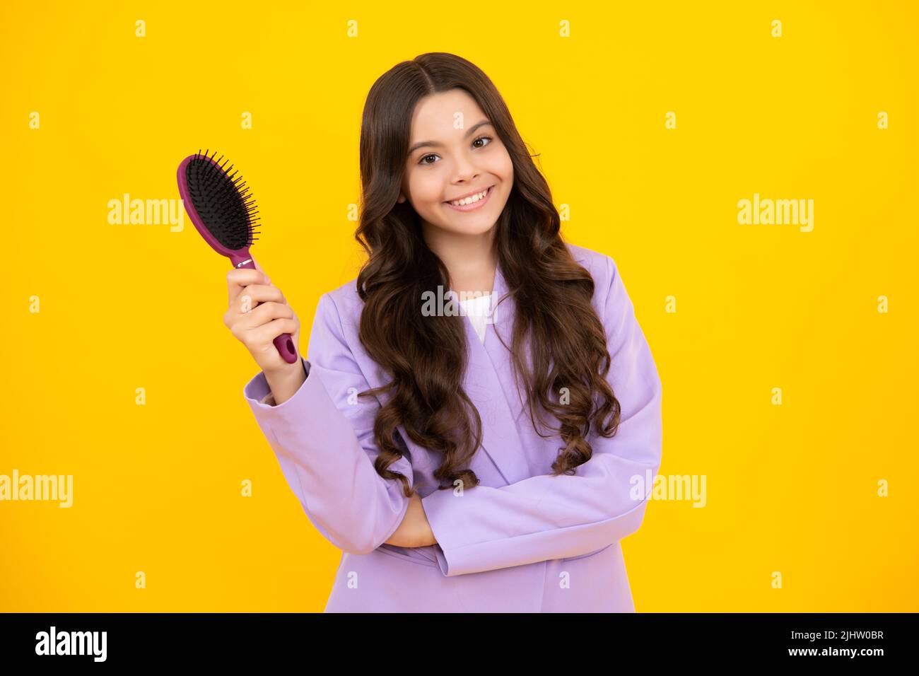 Teenager brushing combing hair with big comb on yellow isolated studio ...