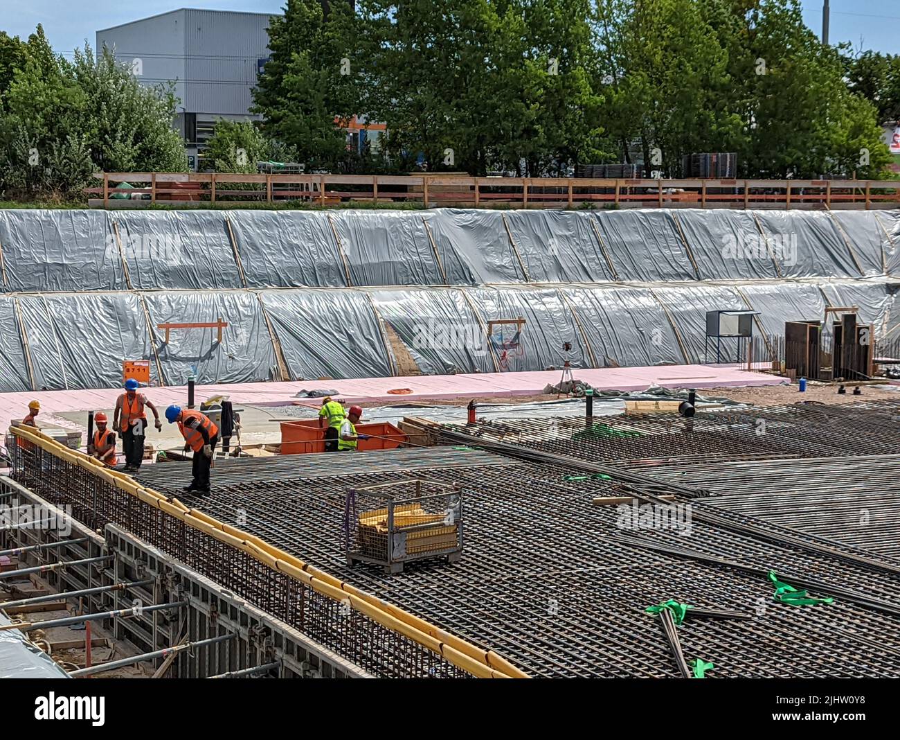 Builders working on building foundation surrounded by plastic sheet ...