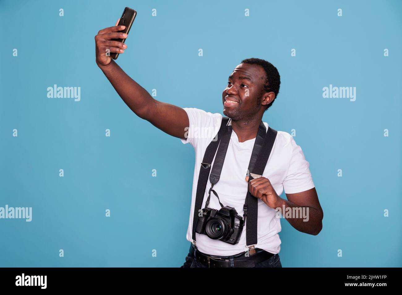 Cheerful photographer taking selfie photo with smartphone while smiling ...