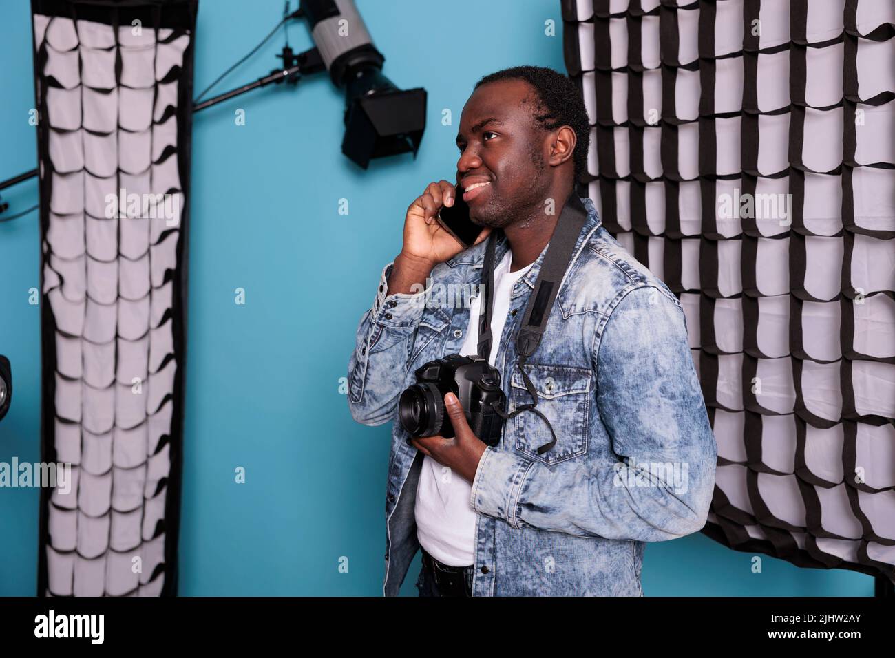 Handsome photographer talking on smartphone while standing in ...