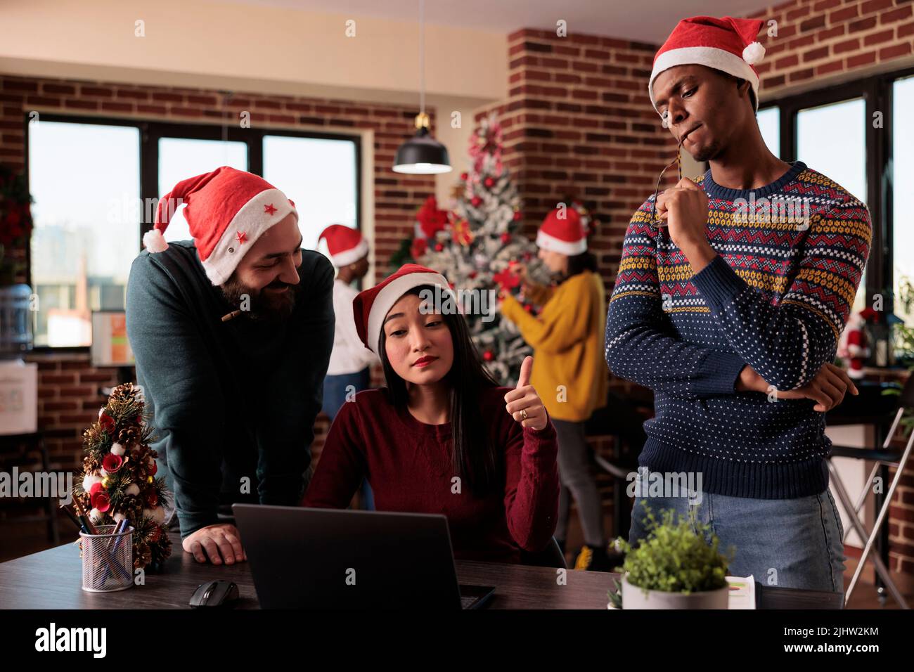 Multiethnic team of coworkers using laptop on christmas, working on ...