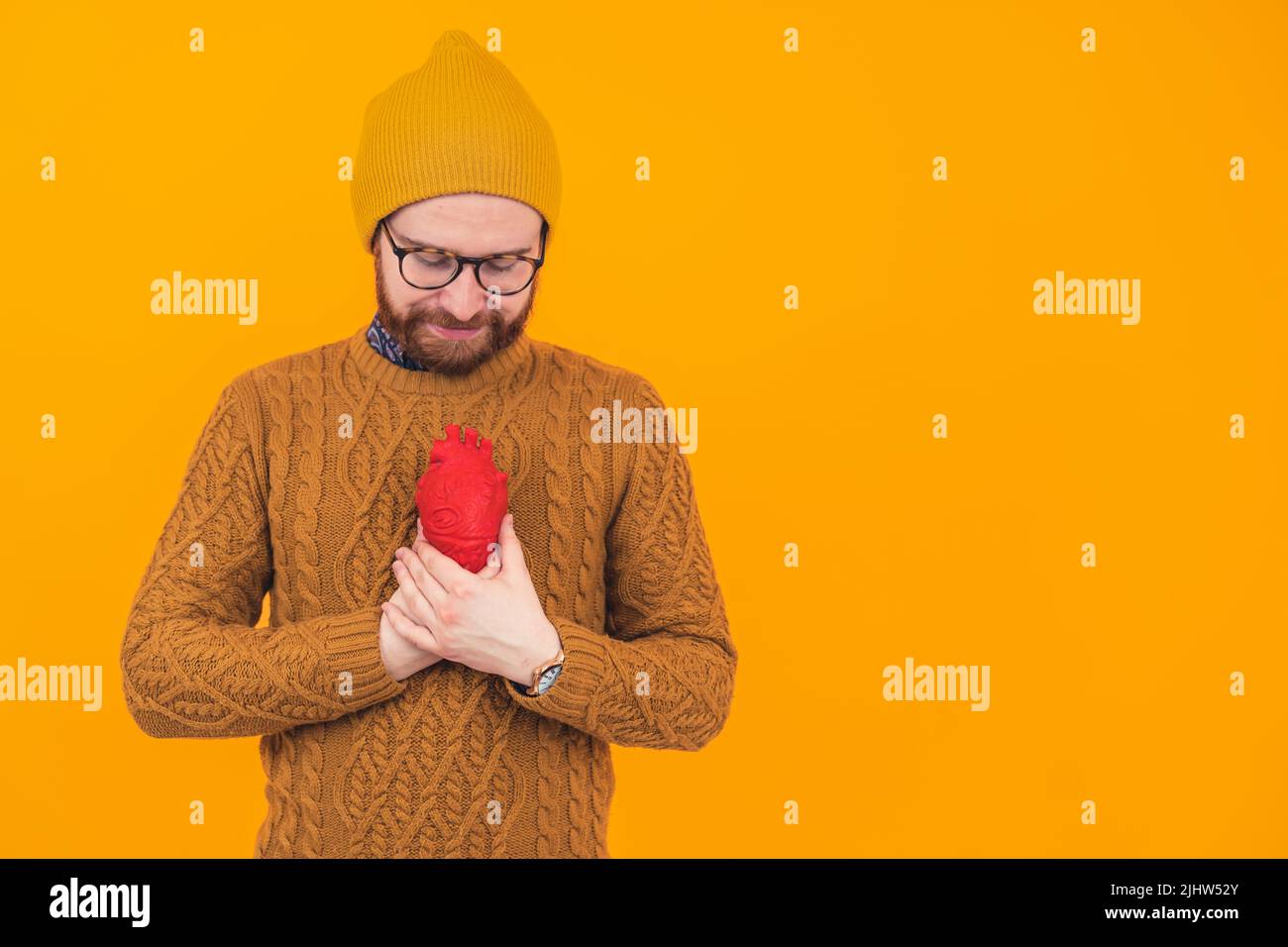 Good-looking stylish bearded man wearing mustard sweater holding an ...
