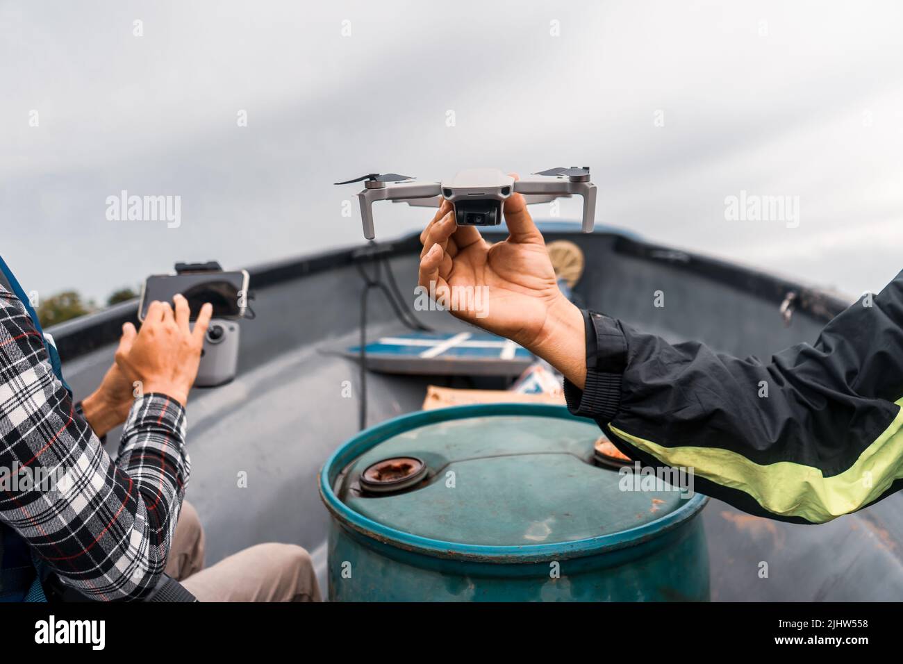 Two unrecognizable Latino men riding a boat and setting up a drone ...