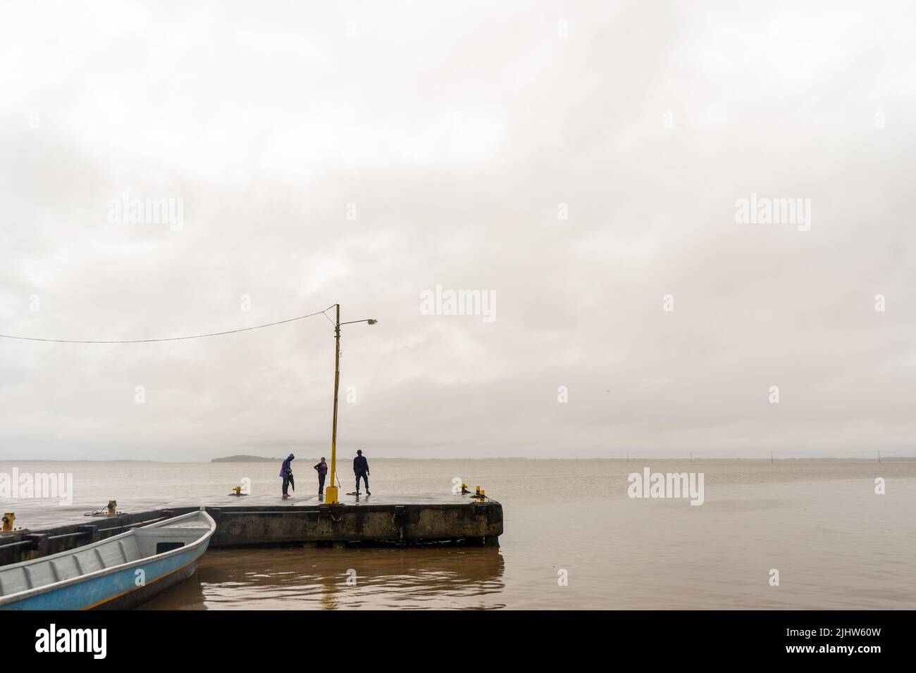 Unrecognizable people walking on a rainy day at the pier of Bluefields ...