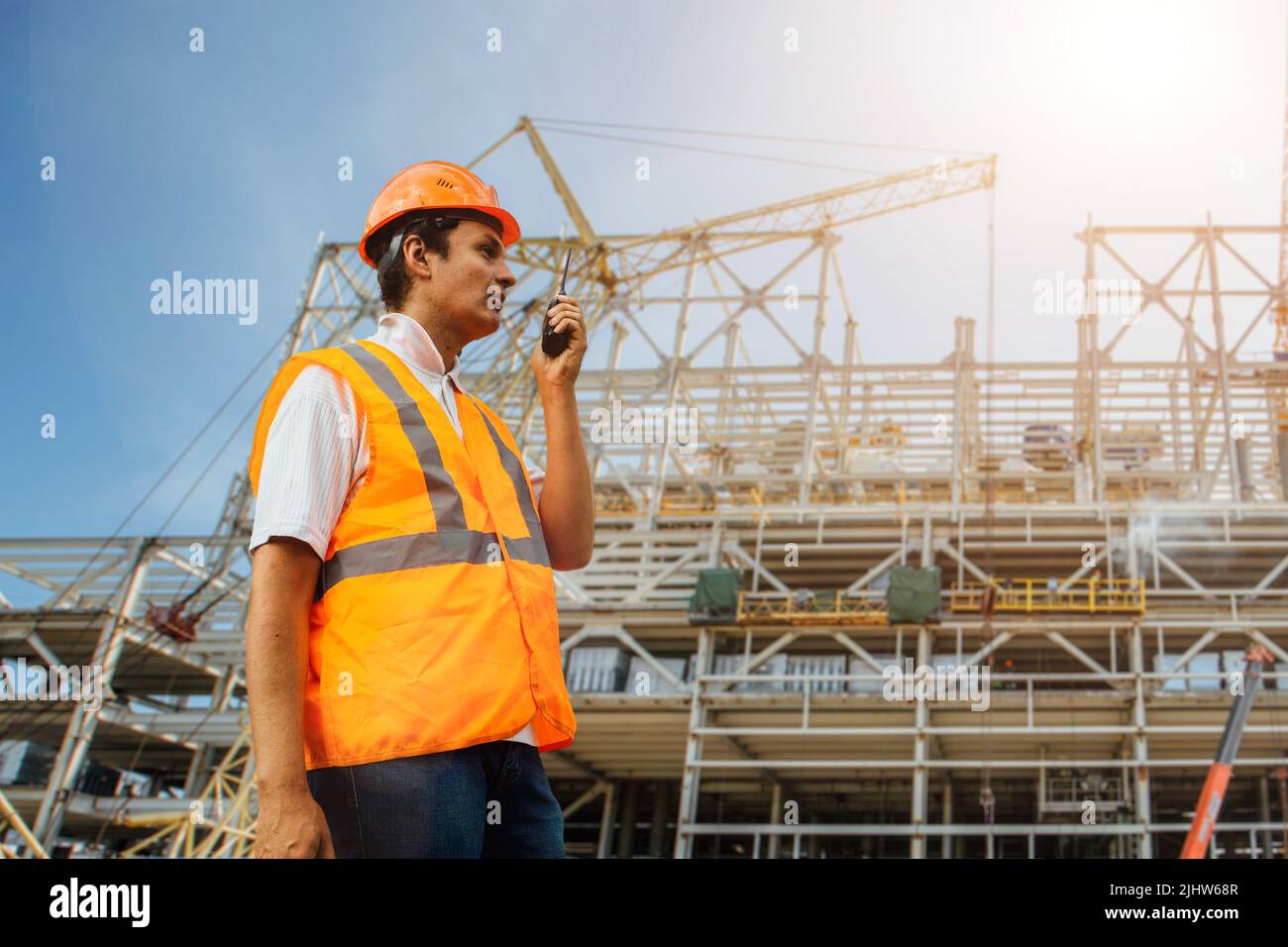 Construction worker in the helmet speaks on the radio Stock Photo - Alamy