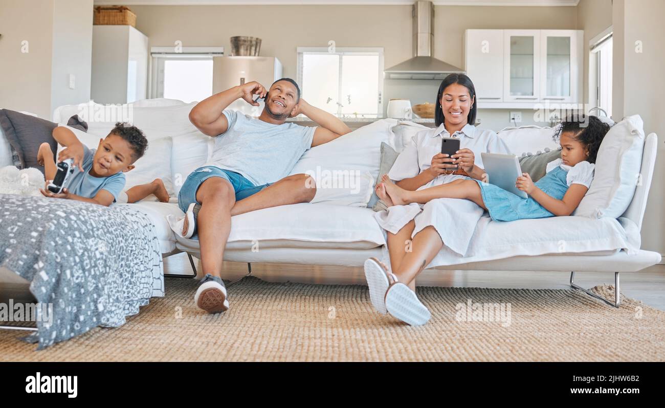 We all chill differently. a young family sitting together using ...
