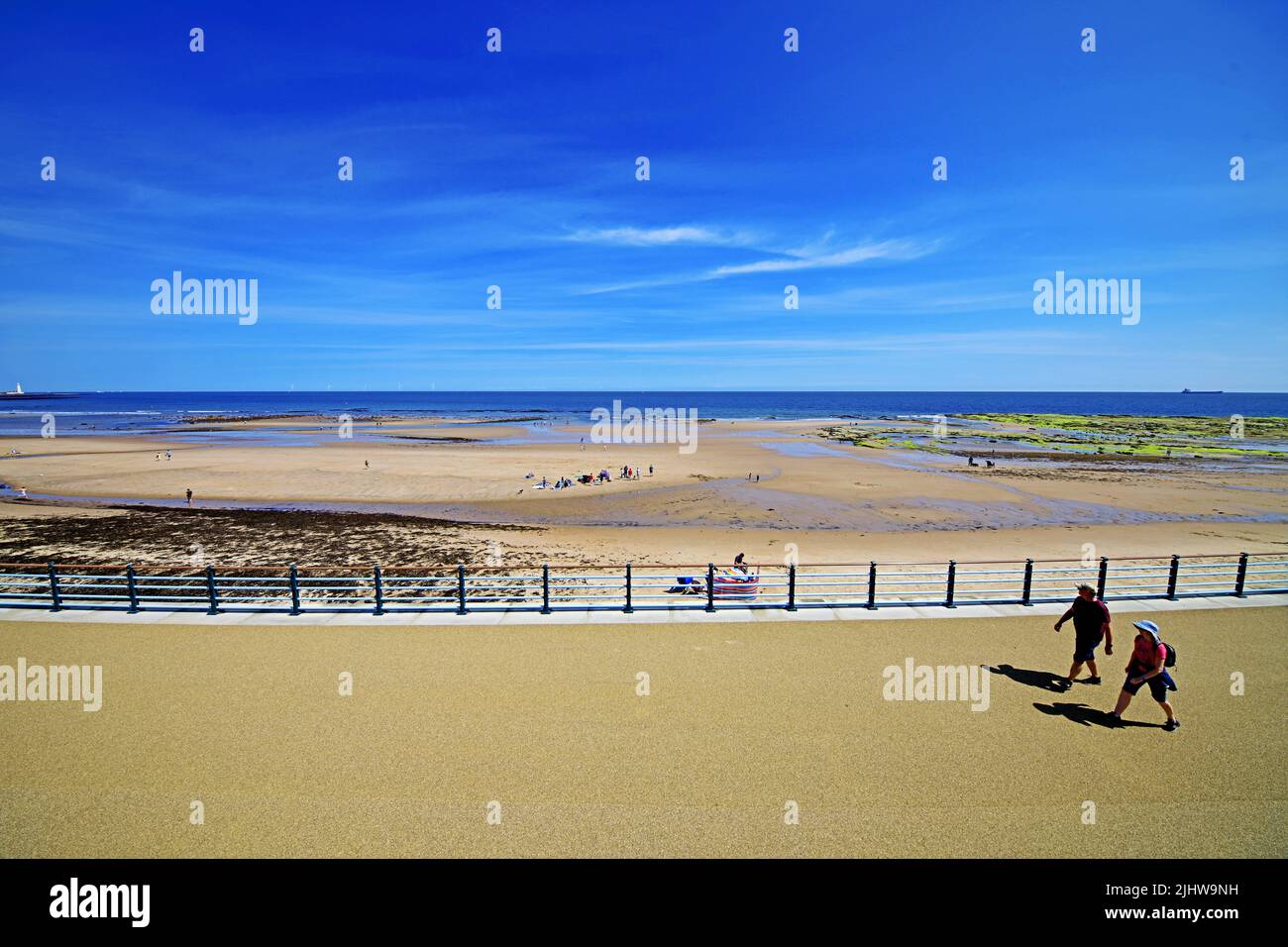 Whitley Bay promenade on a sunny day by the beach with walkers and the ...