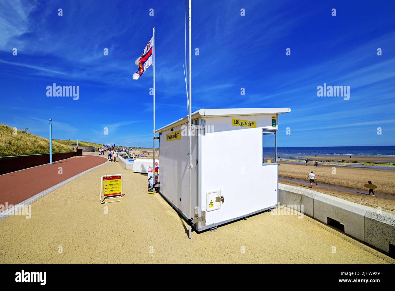 Whitley Bay promenade on a sunny day by the beach with walkers and a ...