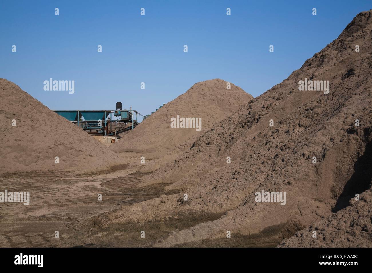 Mounds of excavated fine sand and screening machinery in commercial ...