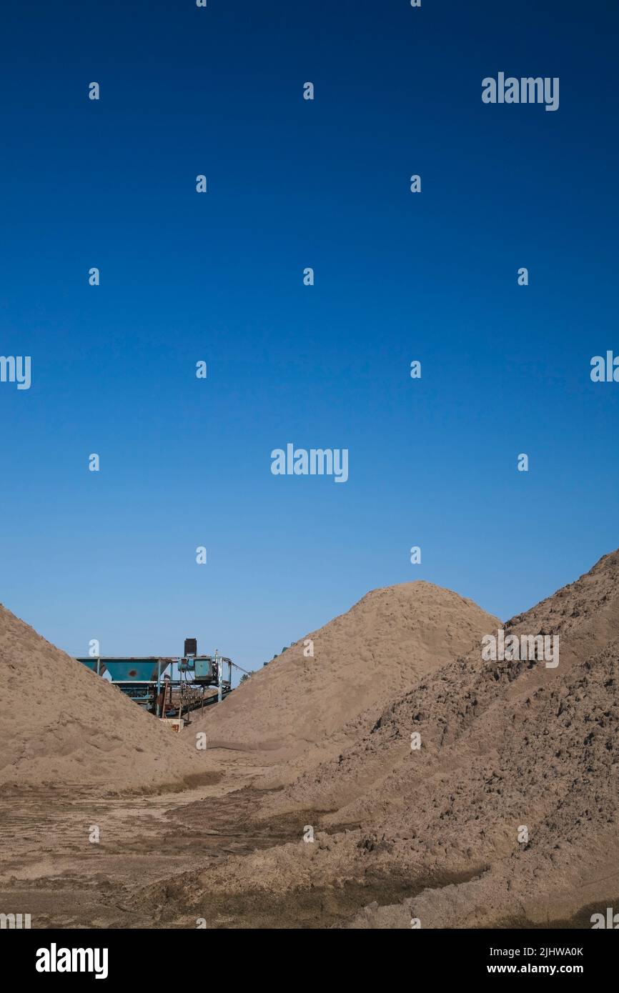 Mounds of excavated fine sand and screening machinery in commercial ...
