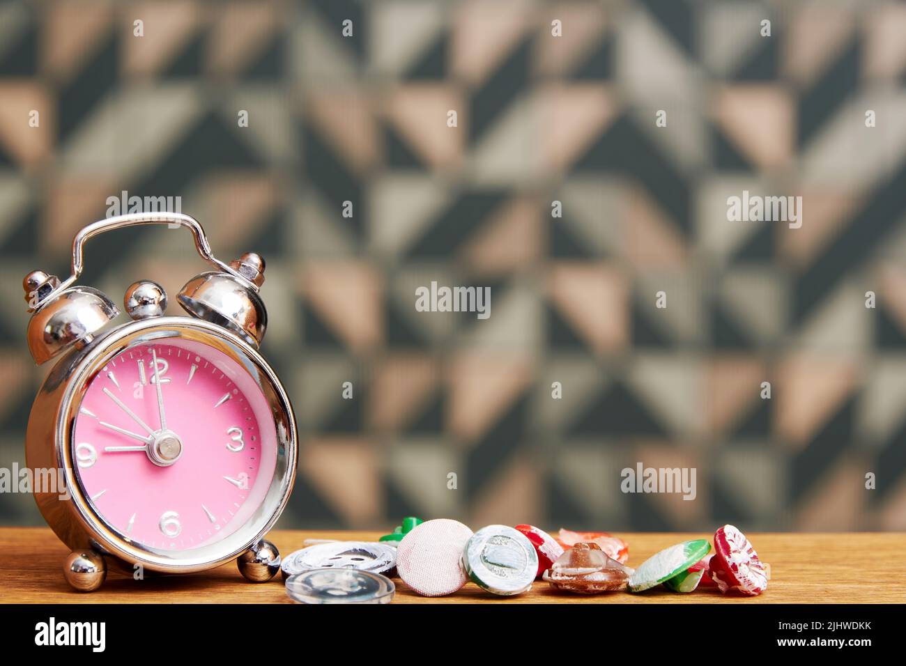 Small fancy alarm clock and colorful buttons on the wooden bed table ...