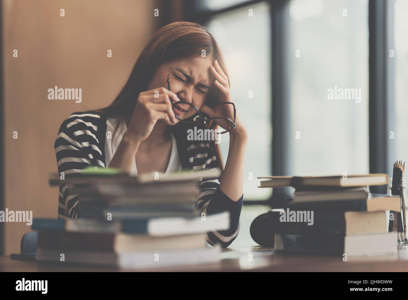 Image of Young woman stressed while reading a book for exam at library ...