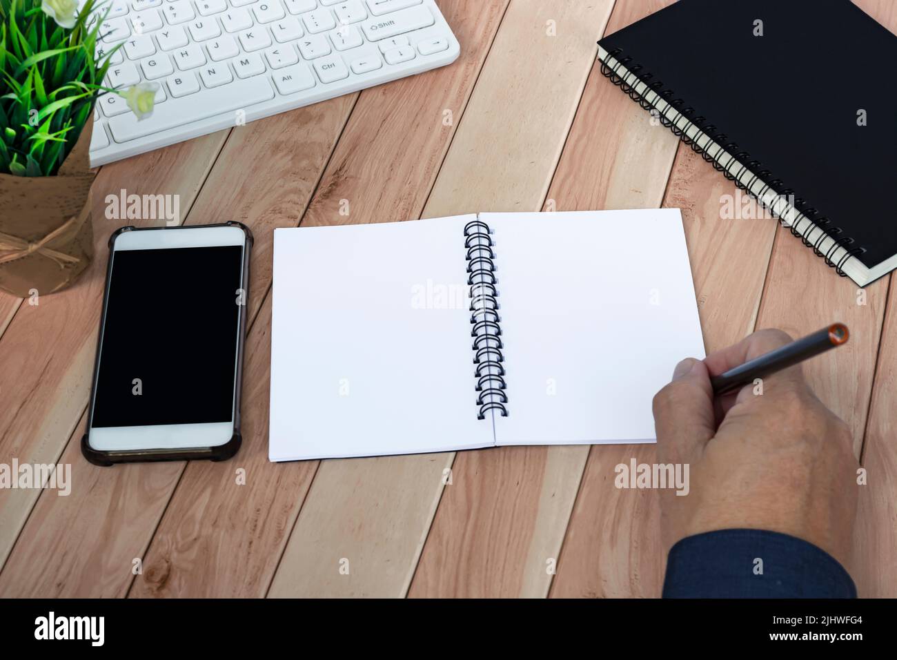 Businessman hands with pen writing notebook on office desk table with ...