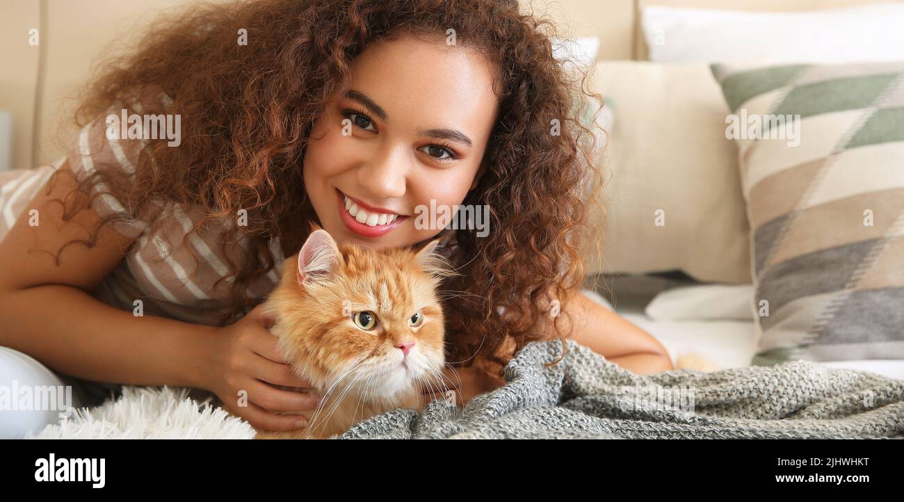 Happy young African-American woman with cute cat in bedroom Stock Photo ...